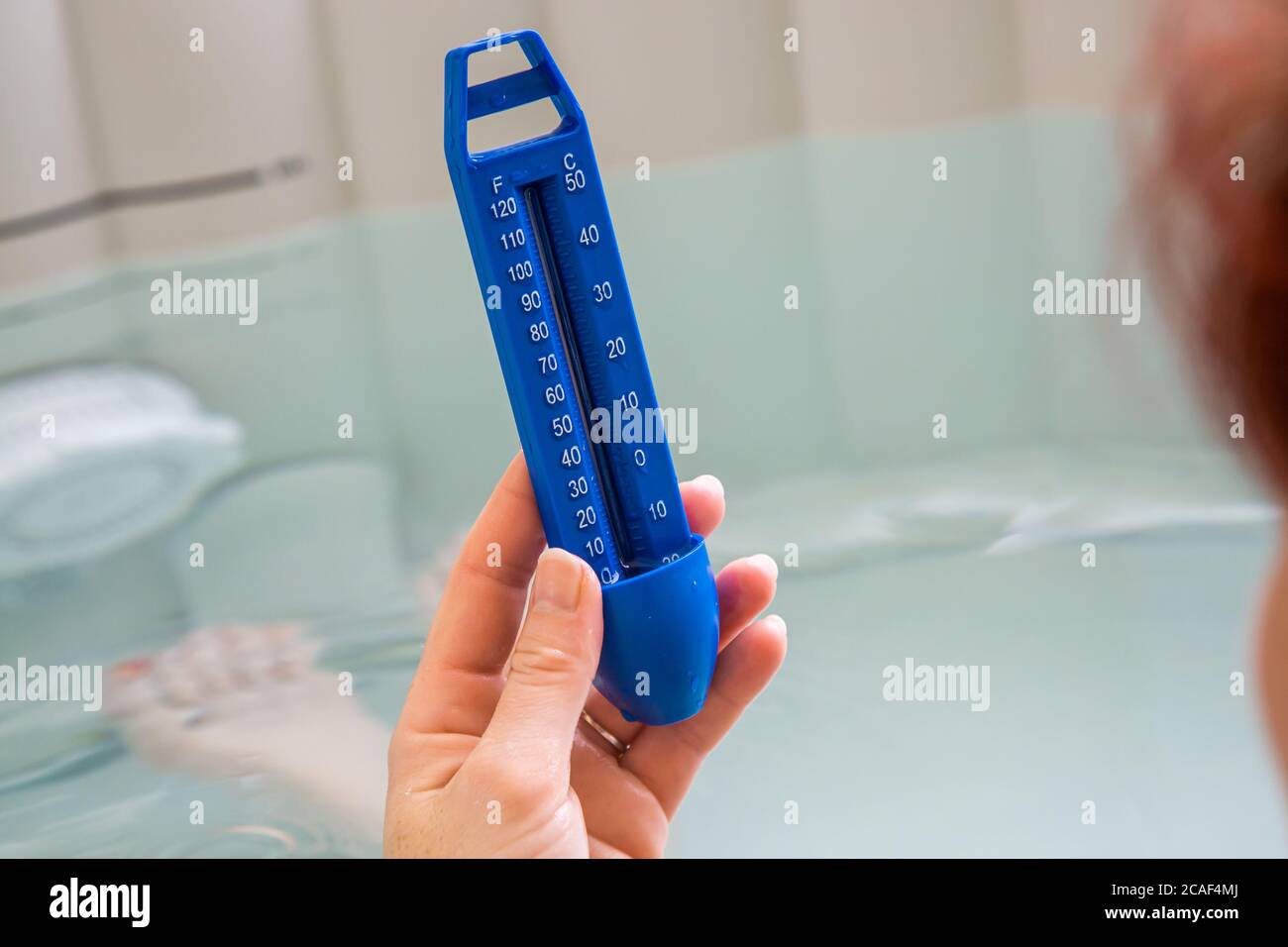 Redheaded woman in a hot tub bath controlling the water temperature ...