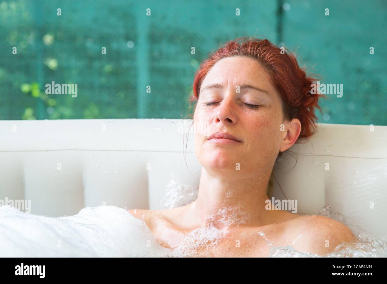 Portrait of Pretty natural redheaded woman relaxing in her jacuzzi ...