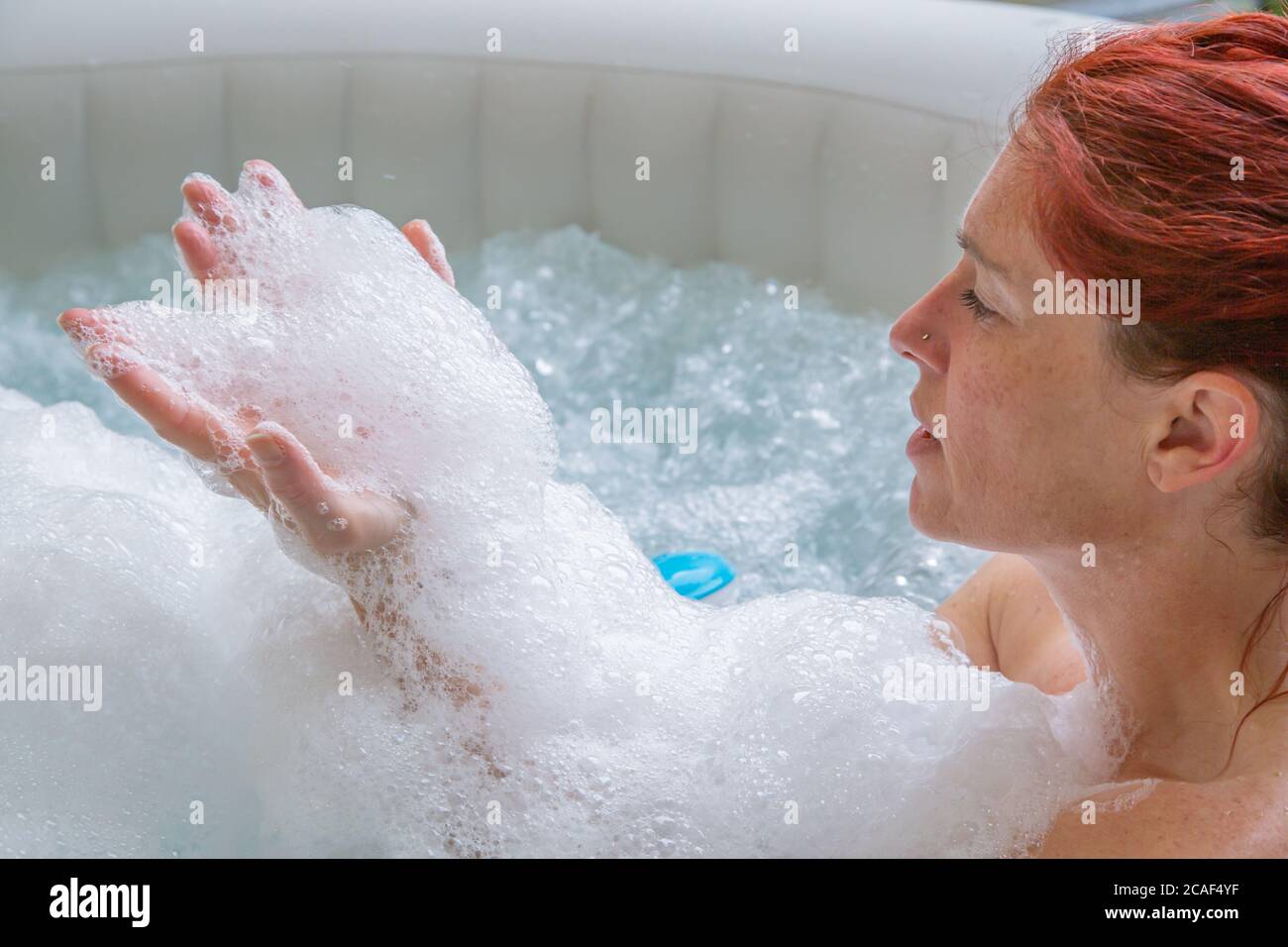 Portrait of Pretty natural redheaded woman relaxing in her jacuzzi ...