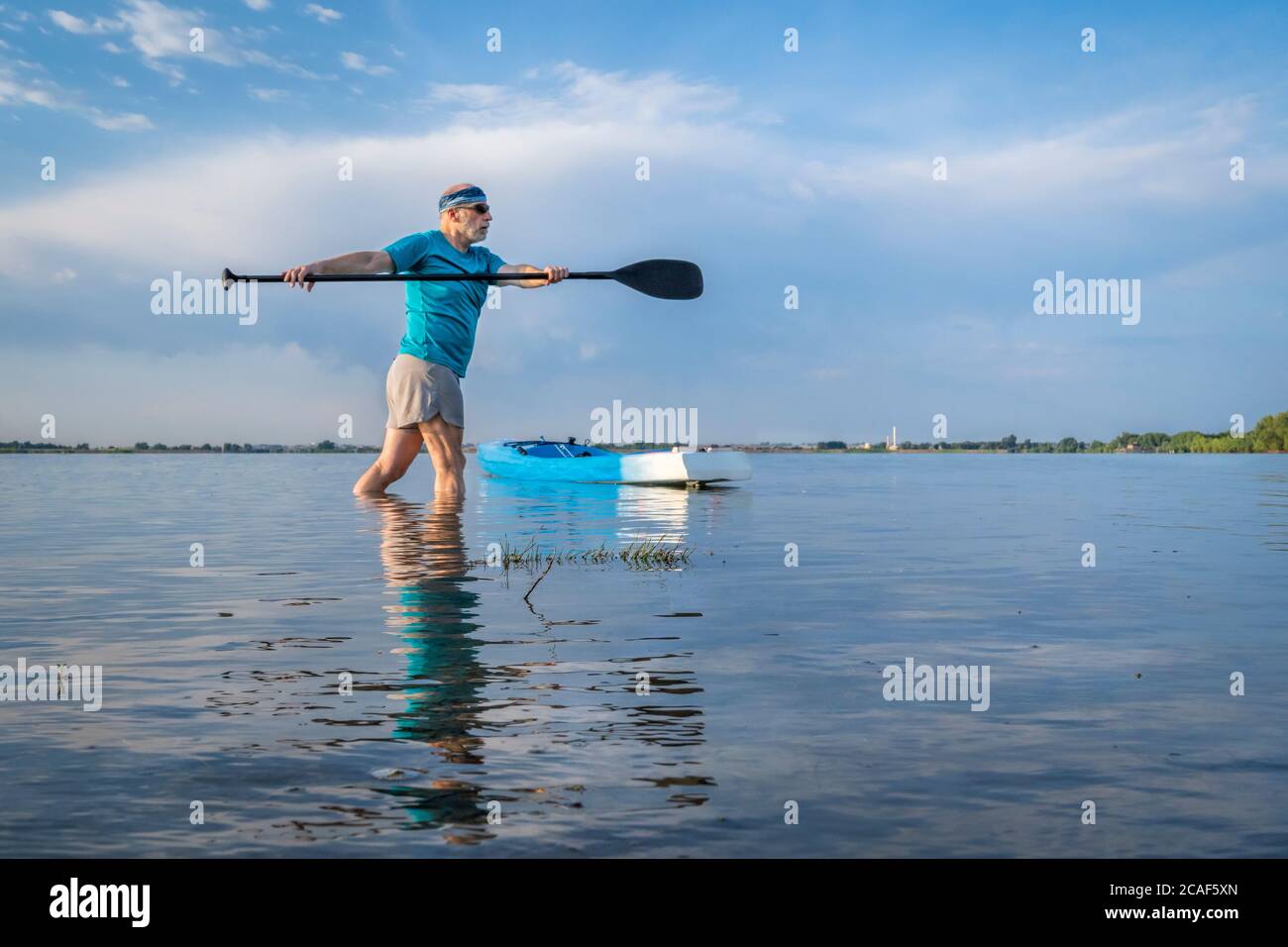 senior paddler is stretching and warming up before morning workout on a ...