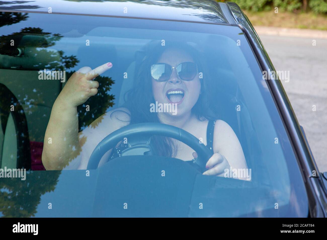 woman is yelling and giving someone the middle finger while driving ...
