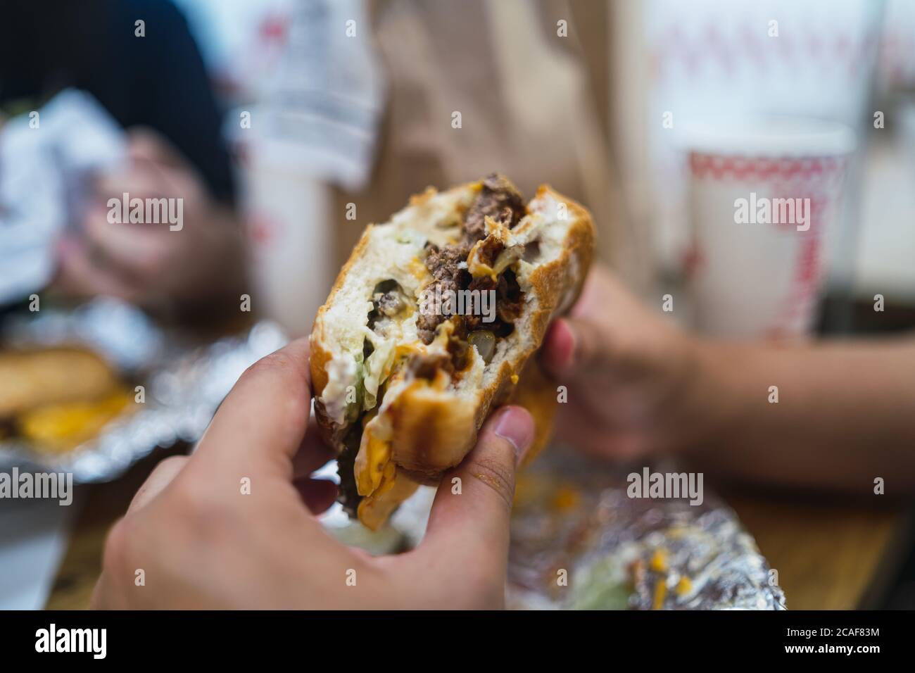 Person eating a burger in a restaurant Stock Photo - Alamy