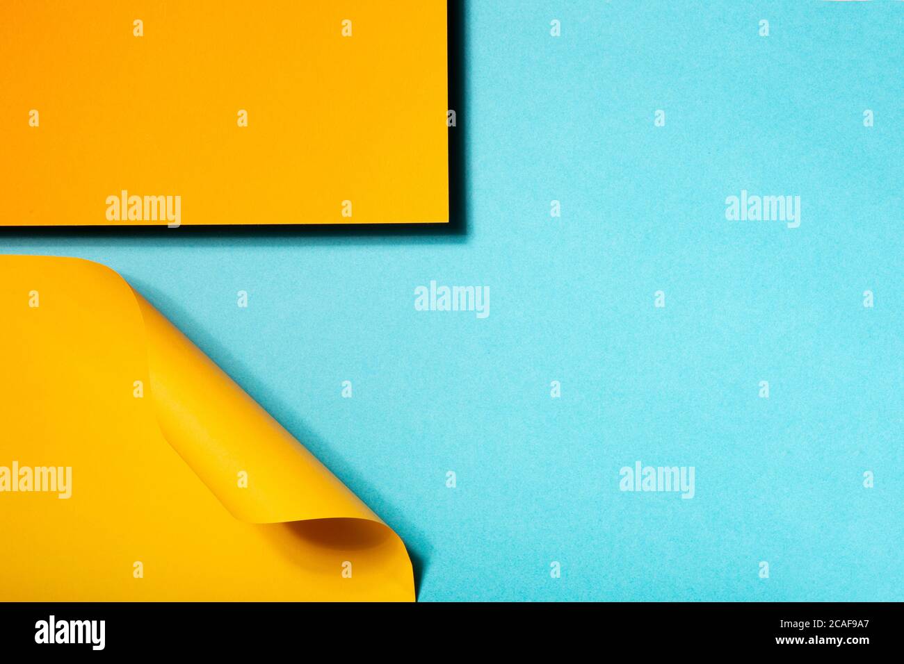 High angle shot of a yellow half-rolled paper on a blue background ...