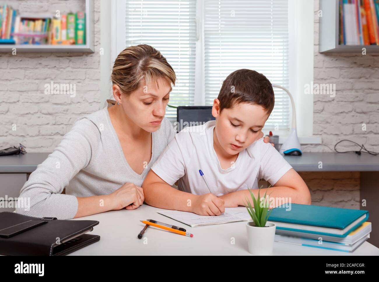 Woman helping his son with schoolwork. Homeschooling, online education ...