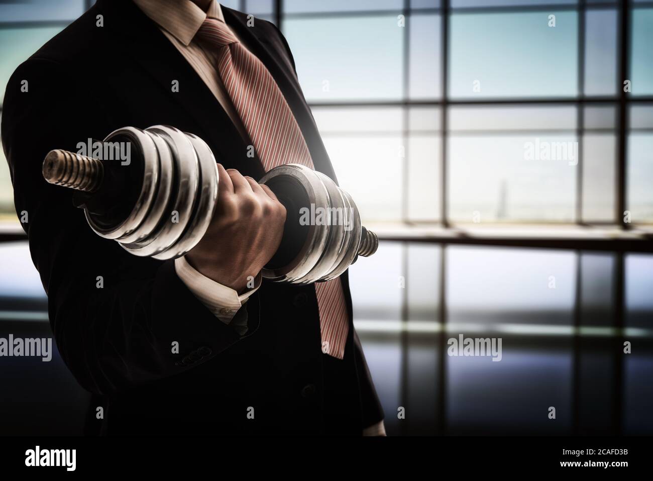 successful business man holding a heavy dumbbell. the concept of ...