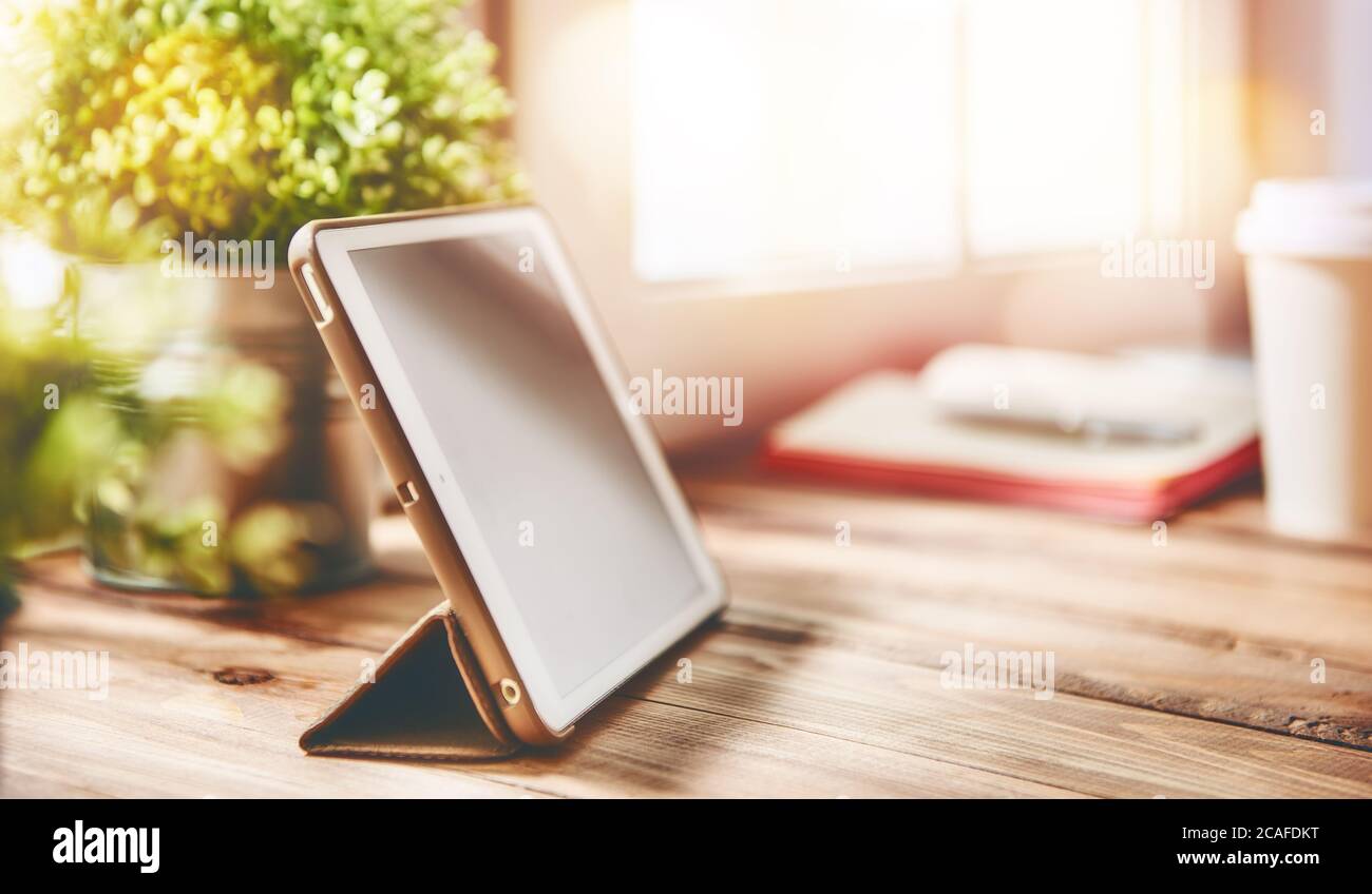 Office workplace with tablet on wood table near the window Stock Photo ...