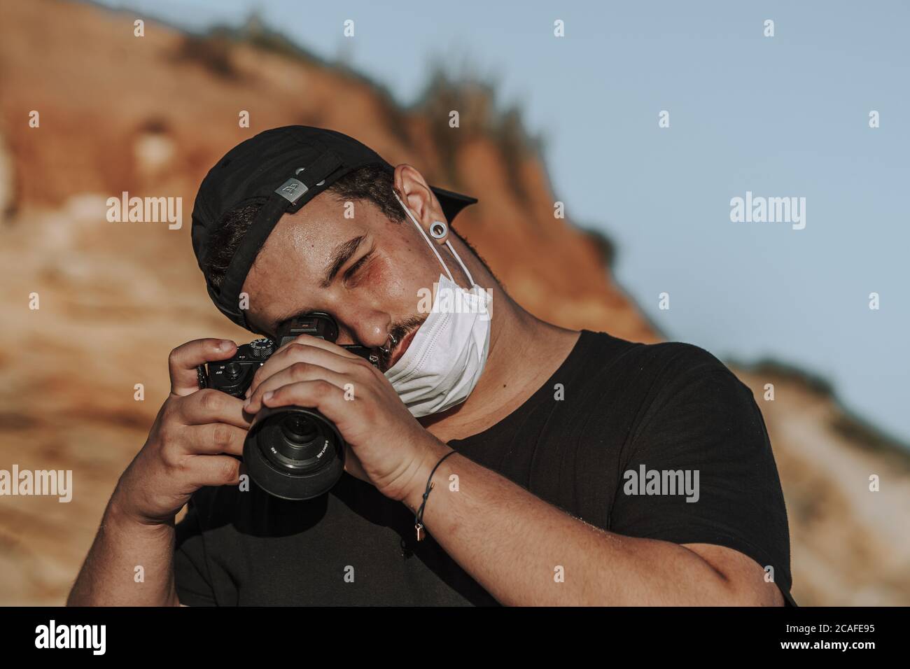 Portrait of a male with a mustache wearing a mask and holding a camera ...