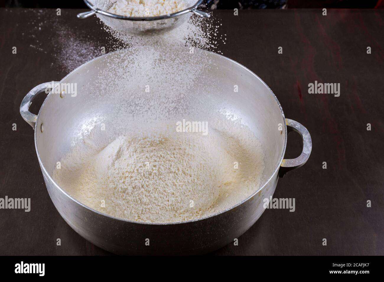 Sifting white flour with sieve in metalic pan Stock Photo - Alamy