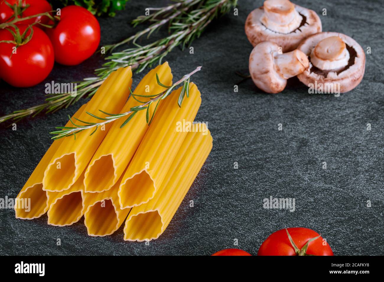 Raw big pasta with tomato, mushrooms and rosemary Stock Photo - Alamy