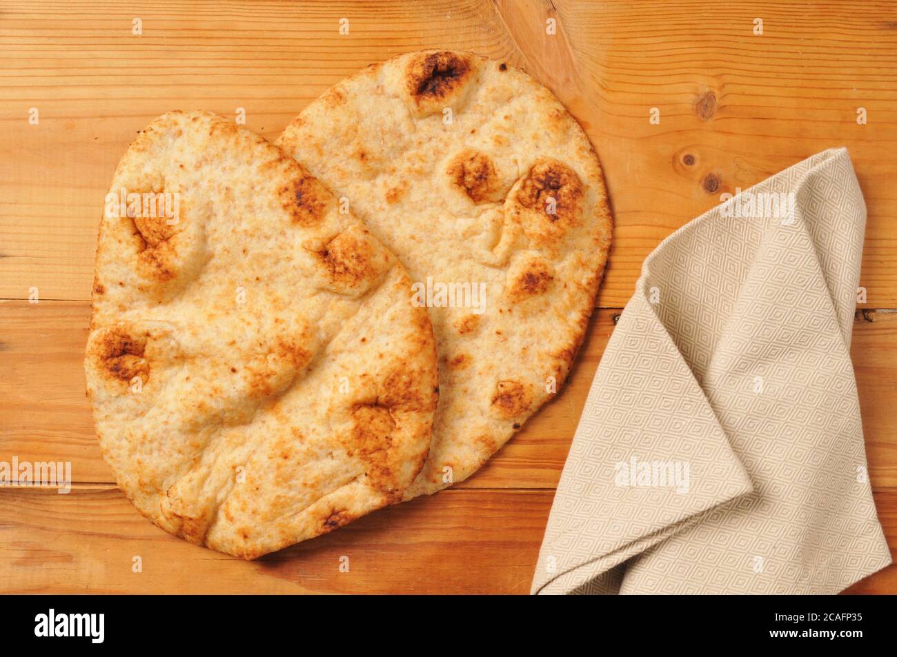 Tandoor baked naan bread on a rustic wooden table Stock Photo - Alamy