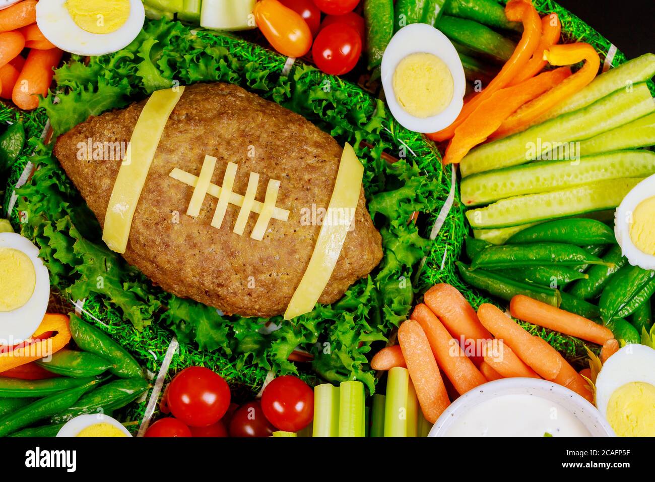 Colorful vegetable platter with egg and meatloaf like a football for ...