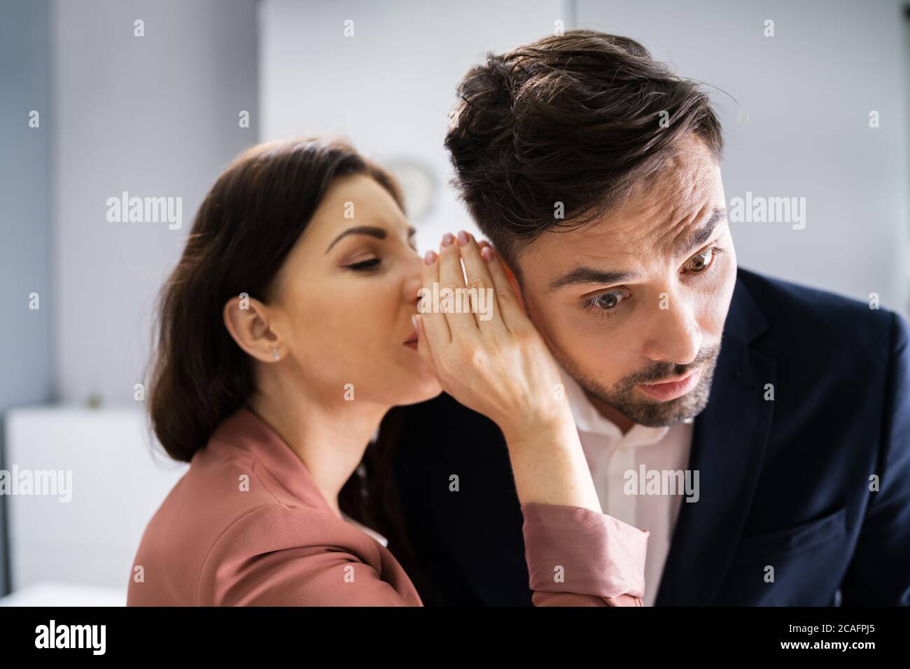 Woman Whispering Gossip In Friend's Ear At Workplace In Office Stock ...