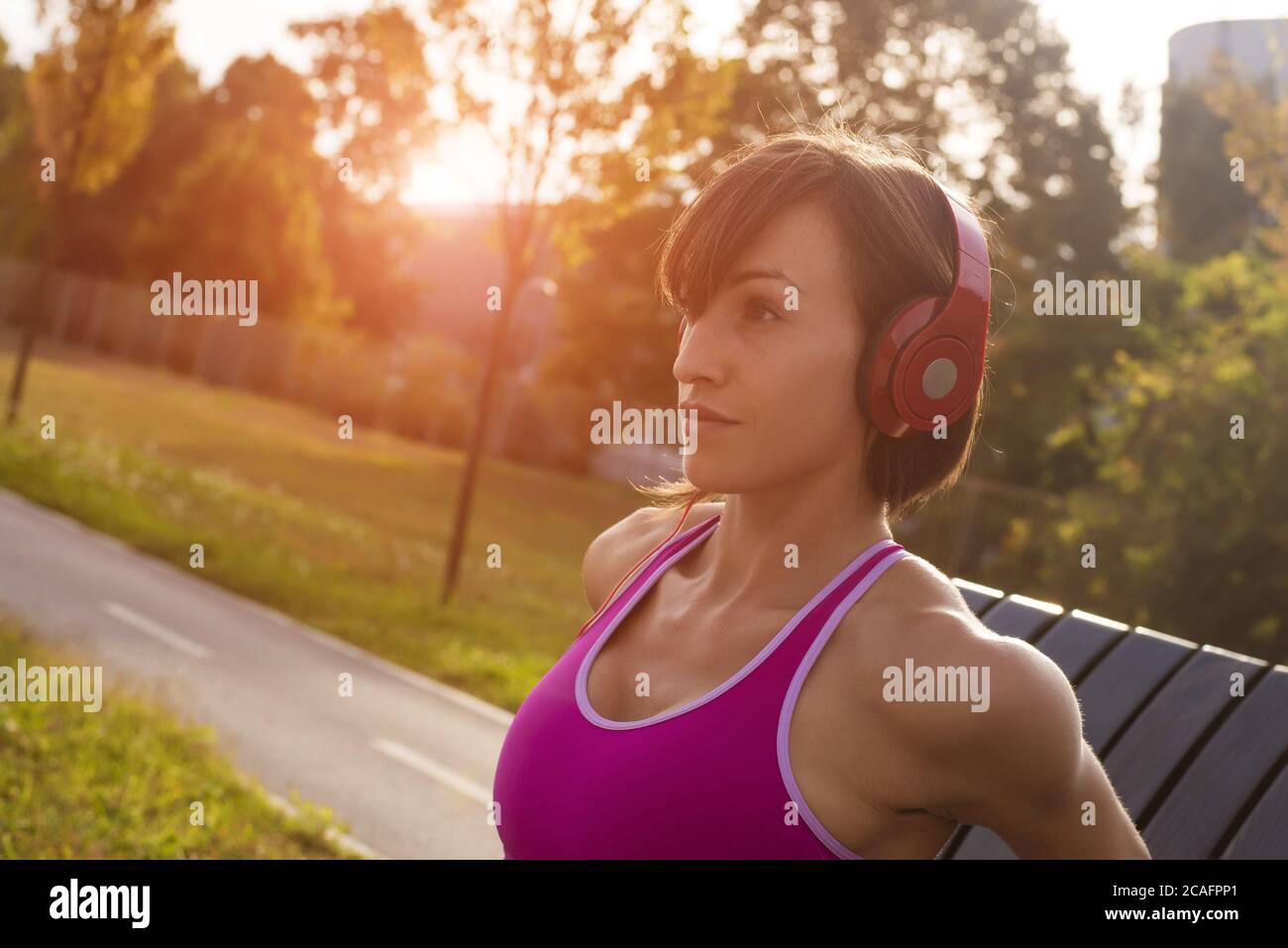 Sporty female listening to music during workout in a park Stock Photo ...