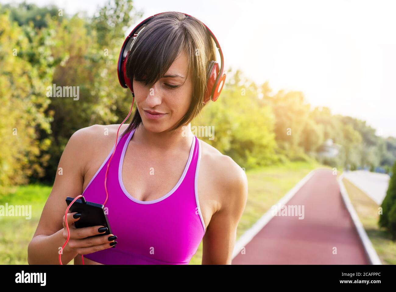 Sporty female listening to music during workout in a park Stock Photo ...