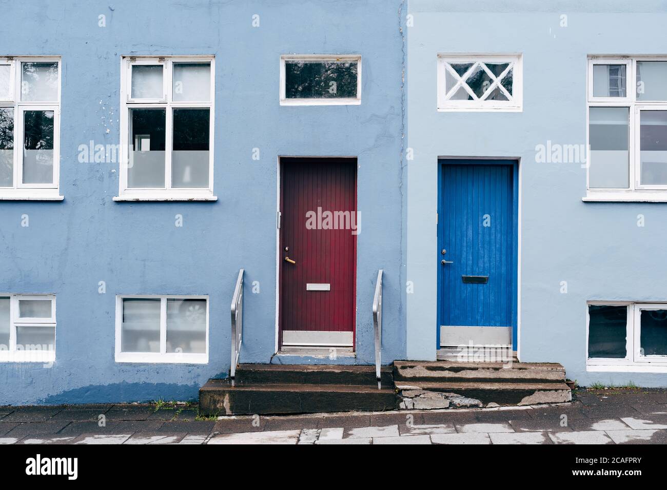 A two-tone building in blue and light blue with two rectangular doors ...