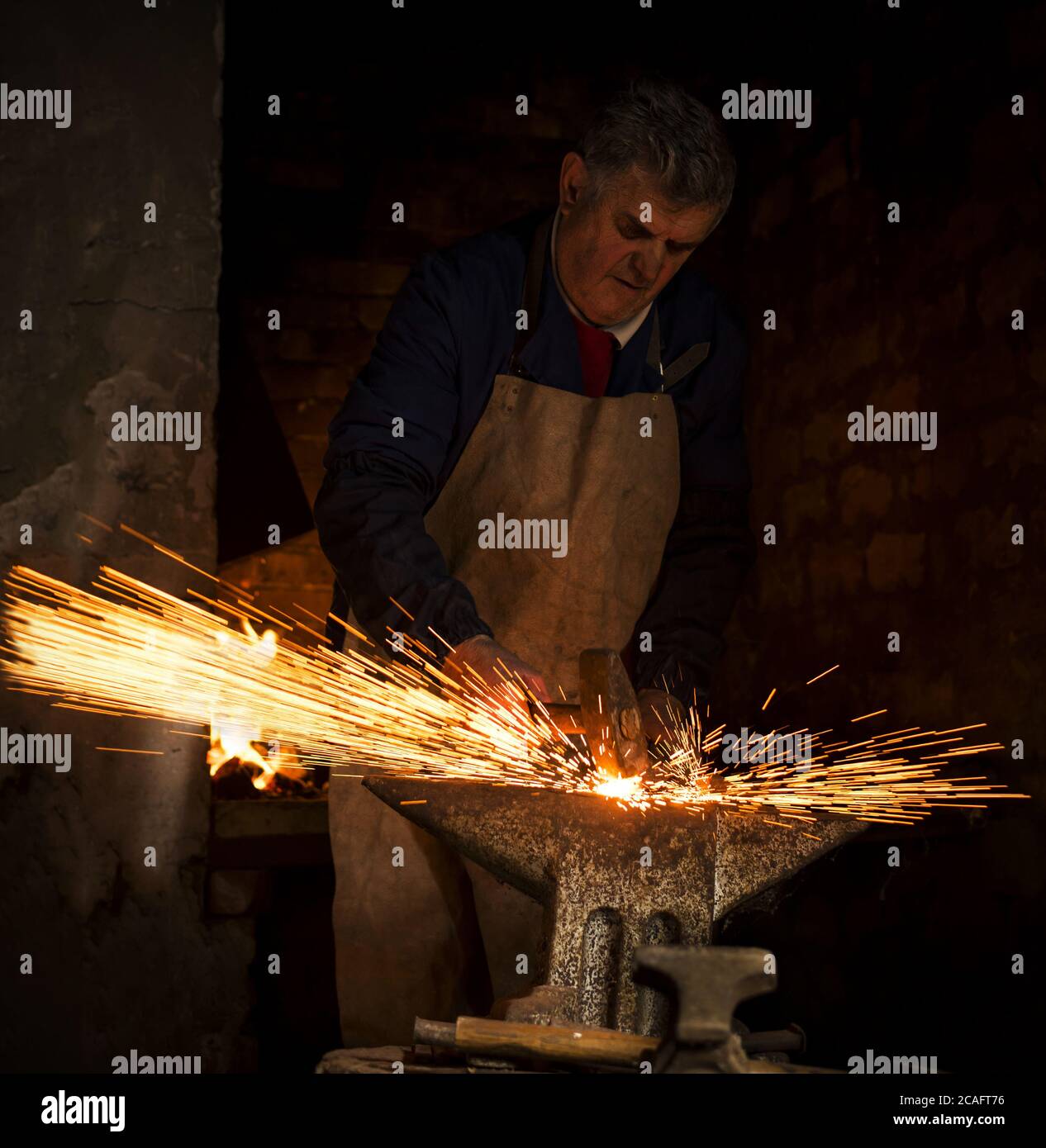 Blacksmith forging the hot metal on the anvil in smithy Stock Photo - Alamy
