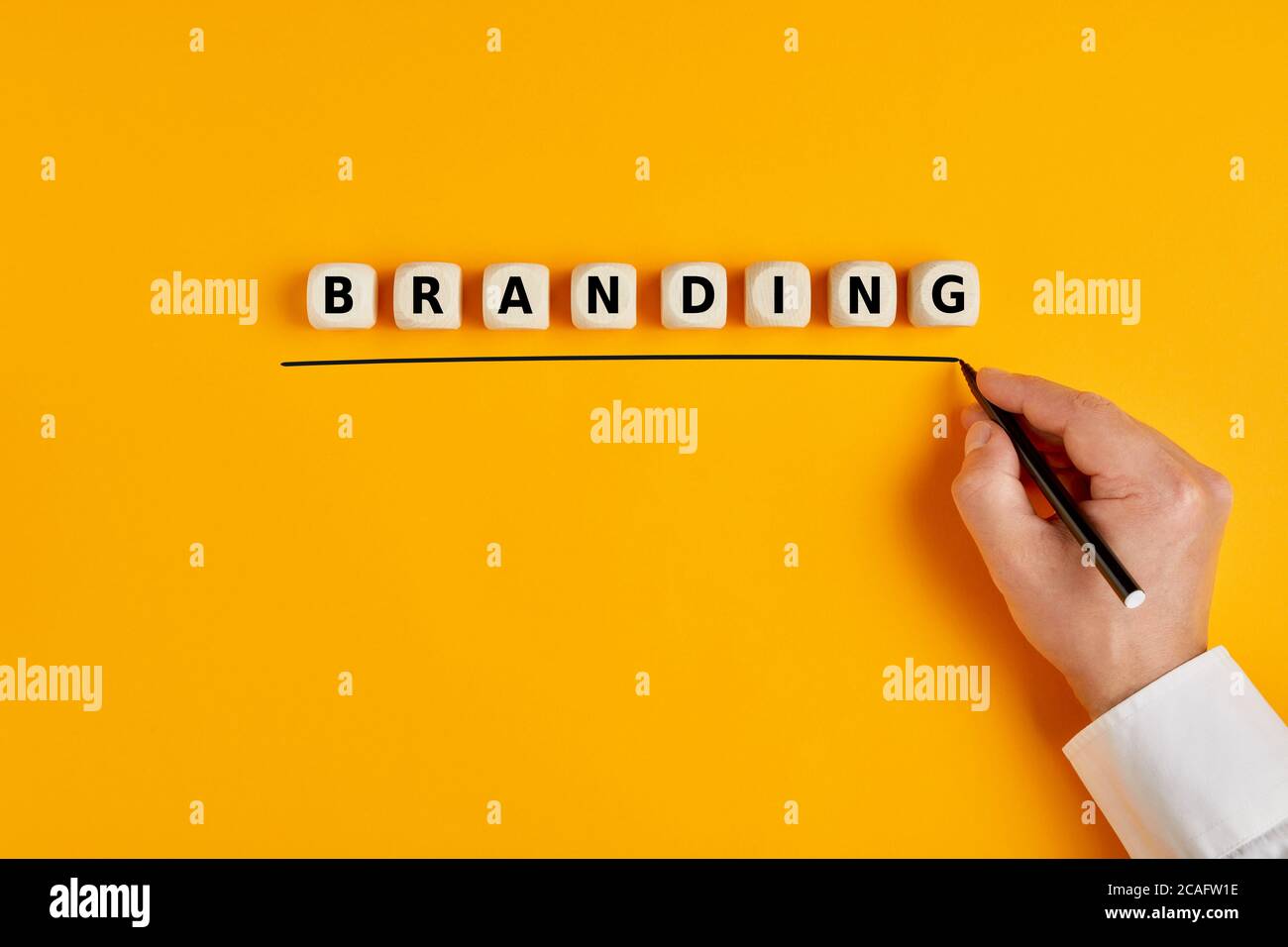 Male hand underlines the word branding written on wooden blocks on ...