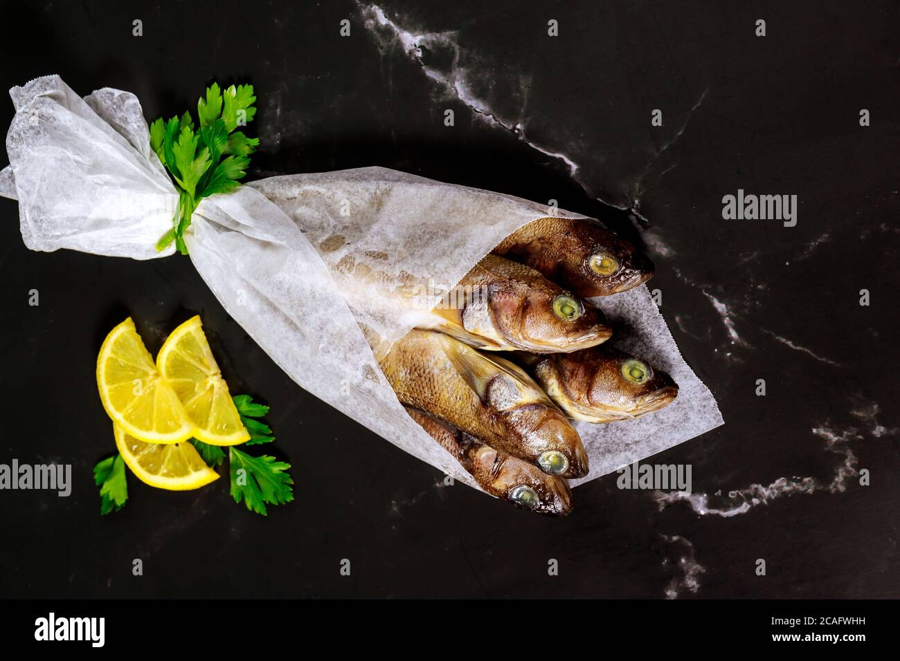Healthy fresh raw fish on black board with lemon and parsley wrapped in ...