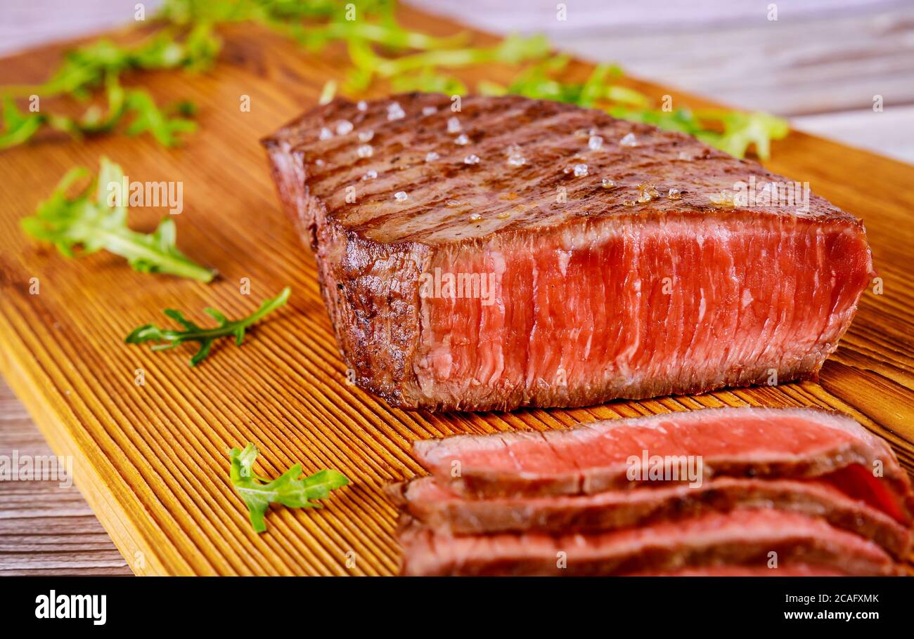 Grilled sliced rare angus beef steak on wooden board. Close up Stock ...