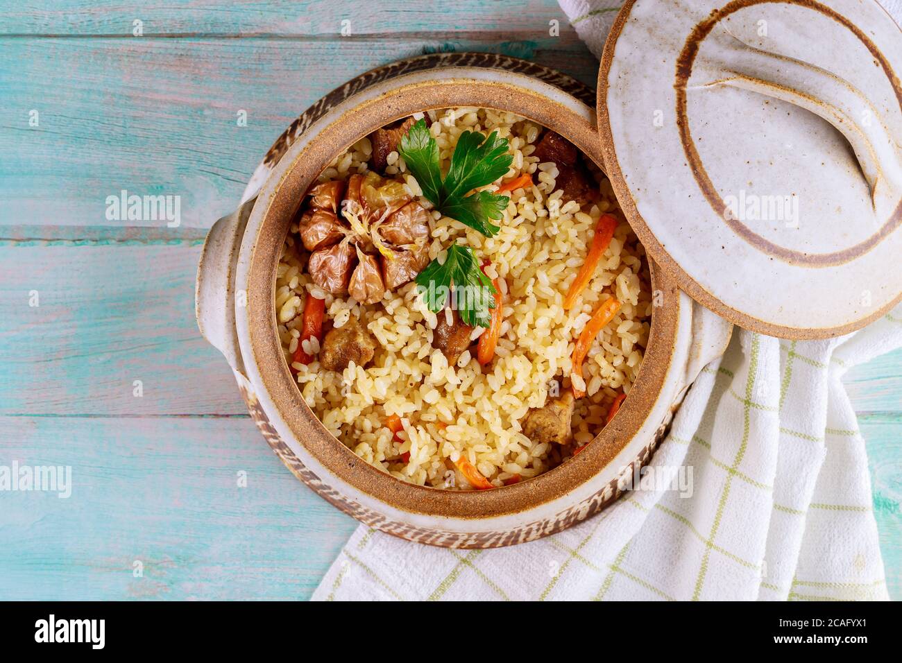 Rice pilaf with lamb, carrots, garlic and indian spices in clay pot ...