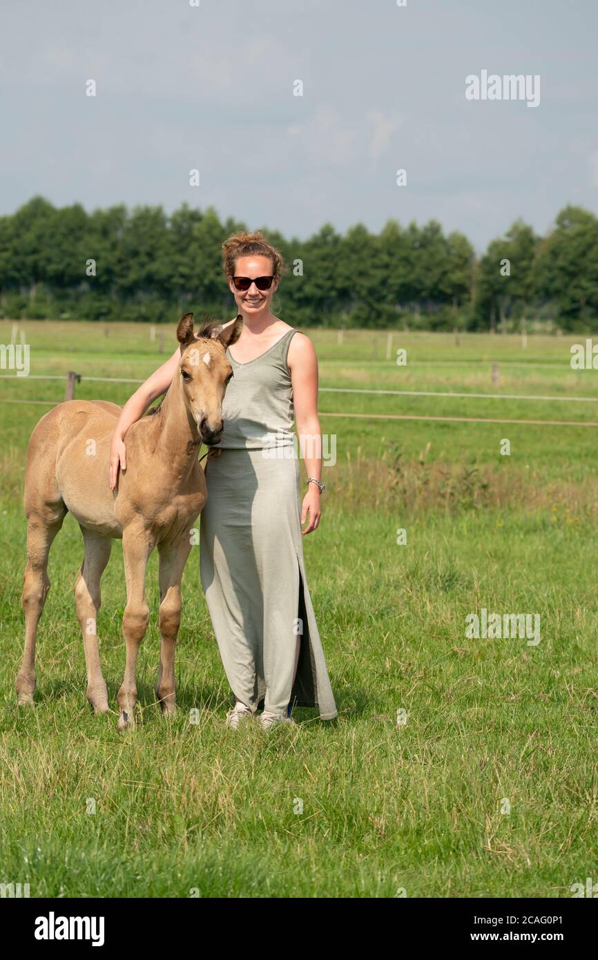 Young woman cuddling with her best friend, falcon color stallion foal ...