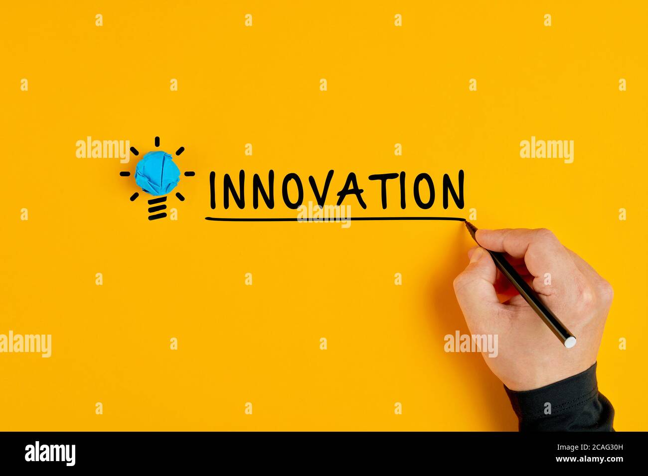 Male hand writing the word innovation next to a light bulb on yellow ...