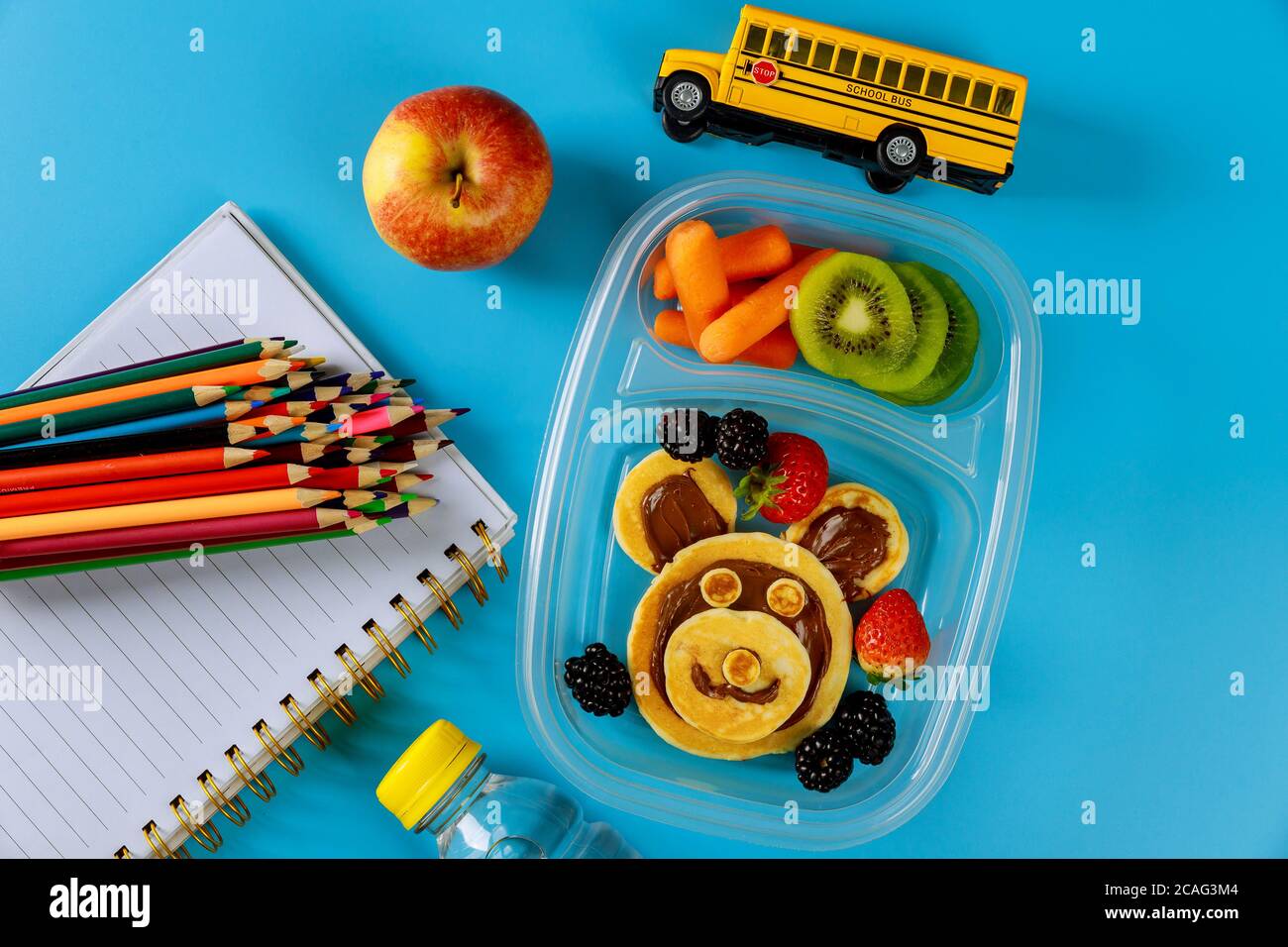 School lunch box with pancakes, fresh fruits and school bus toy with ...
