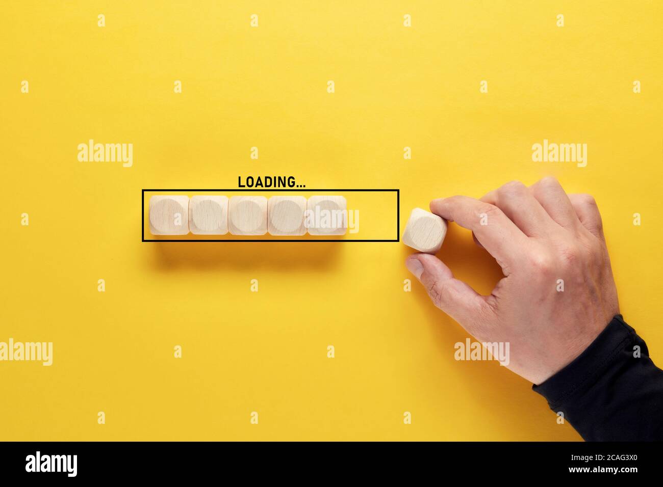 Hand placing wooden cube to complete the loading progress bar on yellow ...
