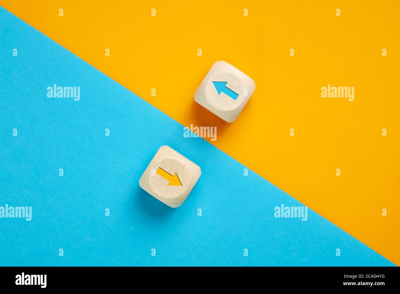 Arrow icons in contrast on wooden cubes moving towards opposite ...