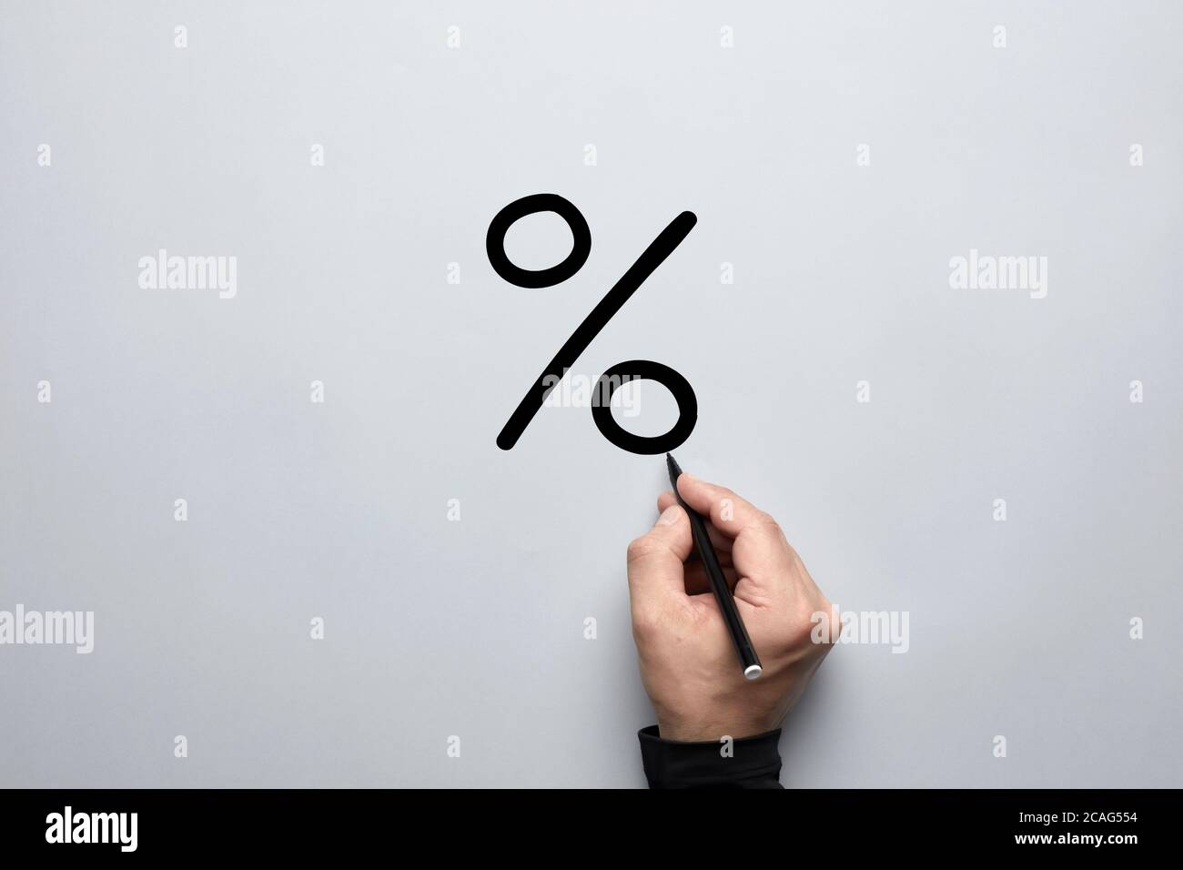 Male hand drawing a big percent sign on gray background with a pen ...