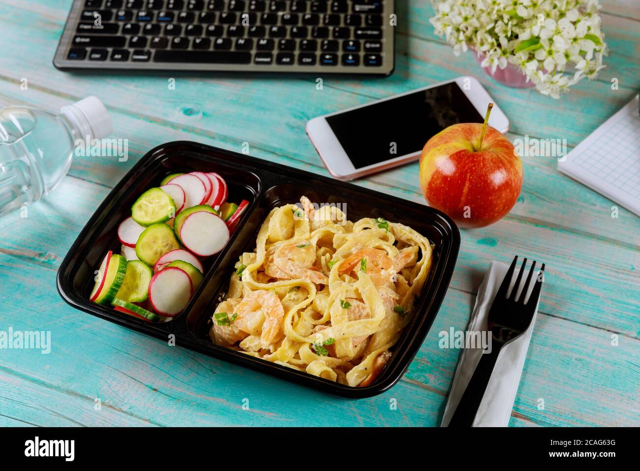 Lunch box container with pasta and shrimps, cucumber and radish on ...
