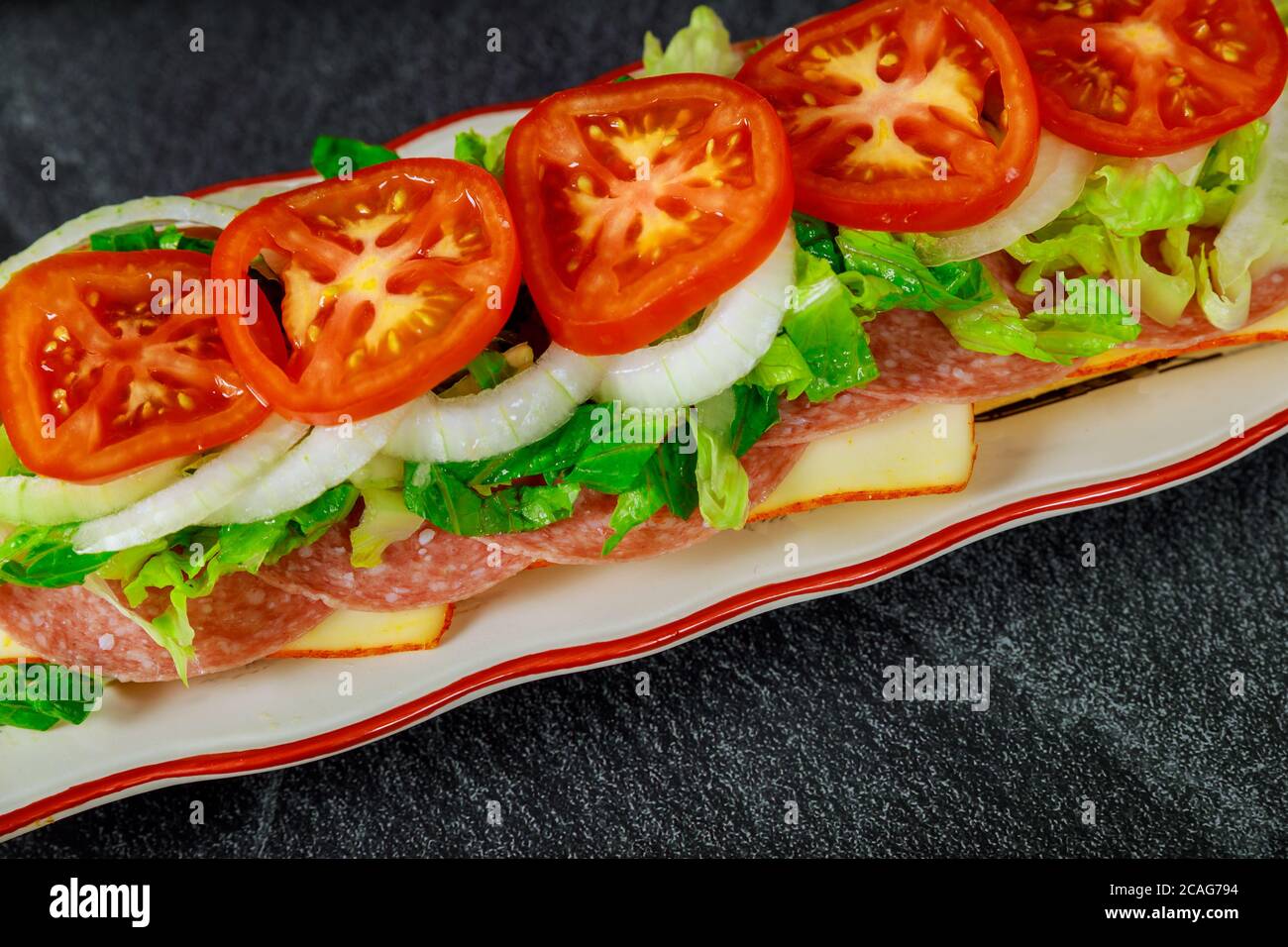 Delicious long sandwich with muenster cheese, salami, and vegetable ...