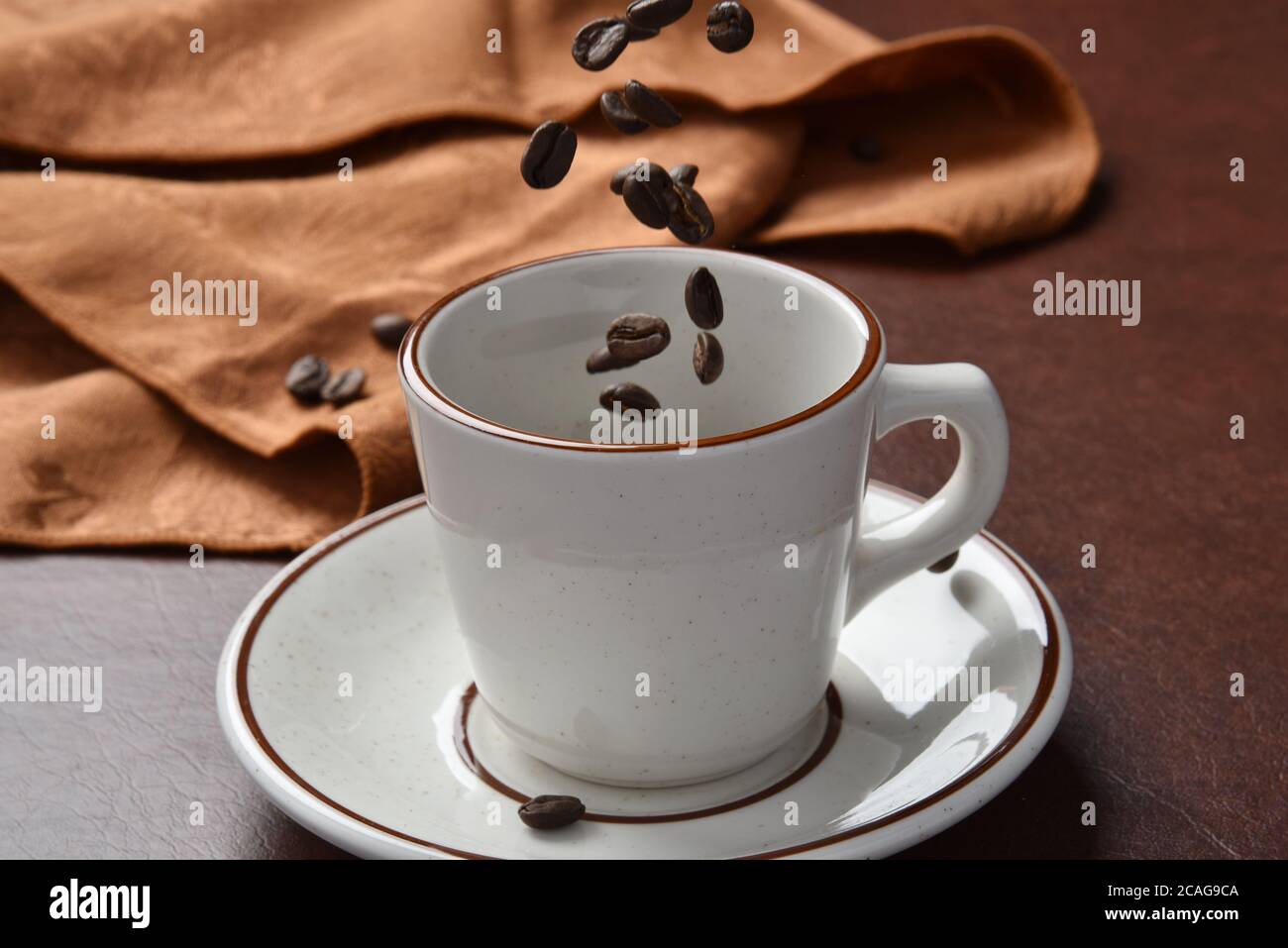 Freeze motion shot of whole dark roasted coffee beans pouring into a ...