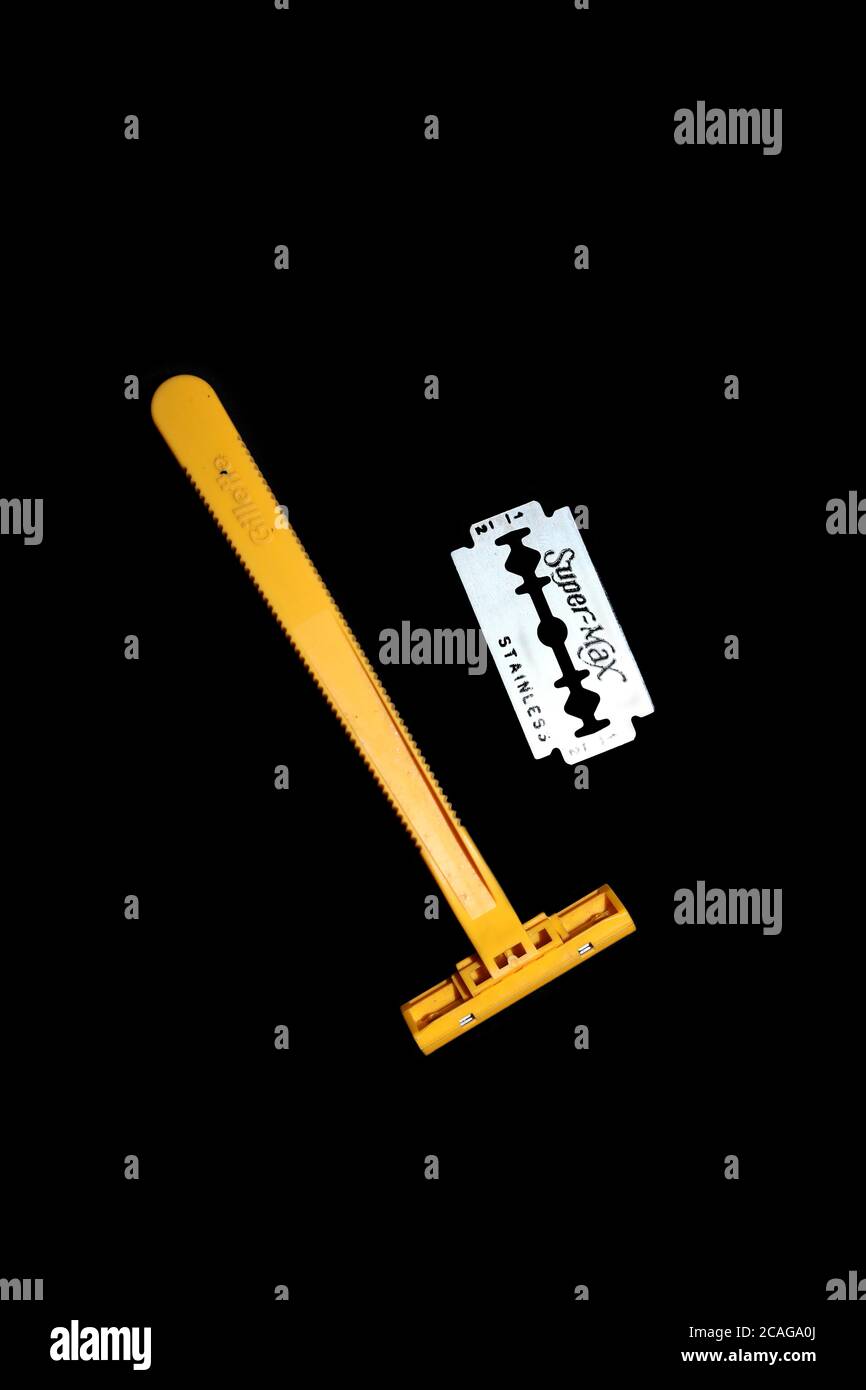 Yellow plastic disposable shaver with stainless steel blade on black ...