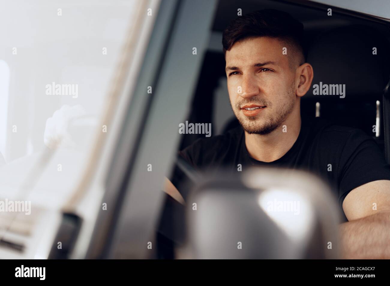 Handsome young man driver looking through the window of his off-road ...