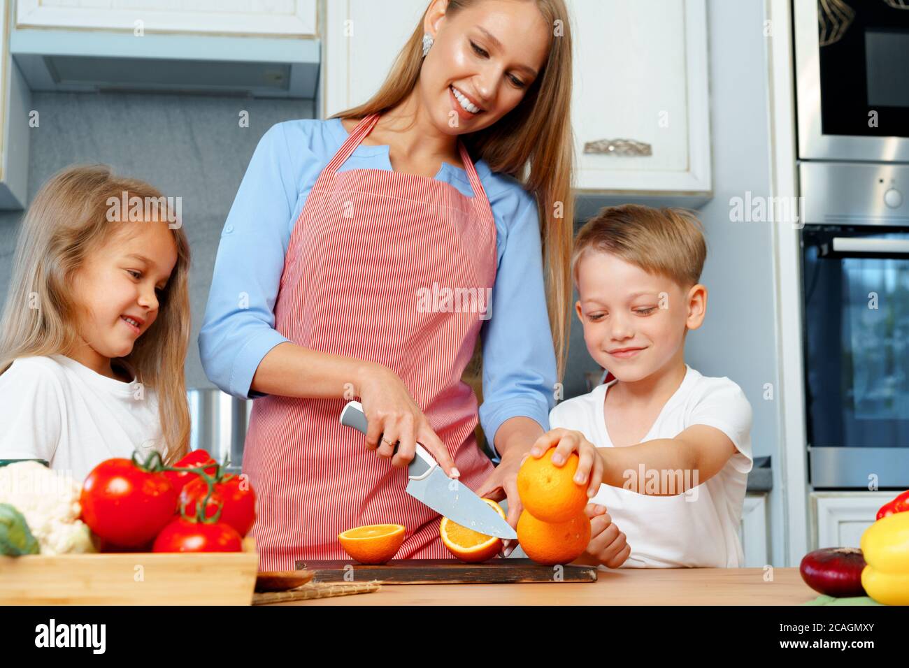 Mother cooking with her children in kitchen Stock Photo - Alamy