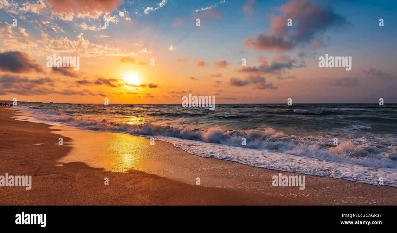 Colorful sunset with wave splashes on the beach Stock Photo - Alamy