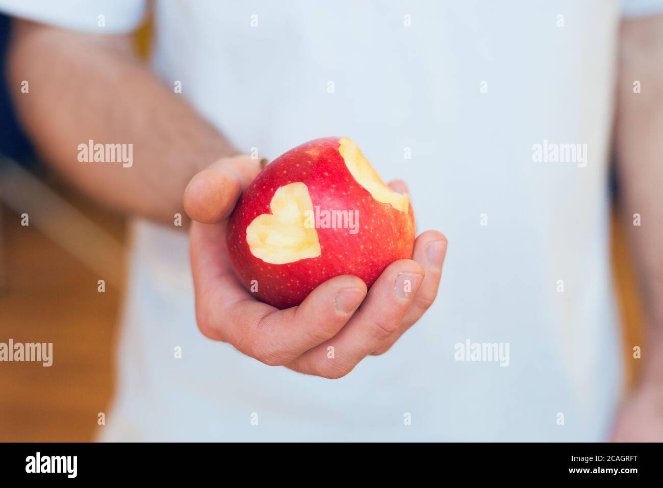 Bitten red apple with cutted heart in the male hand Stock Photo - Alamy