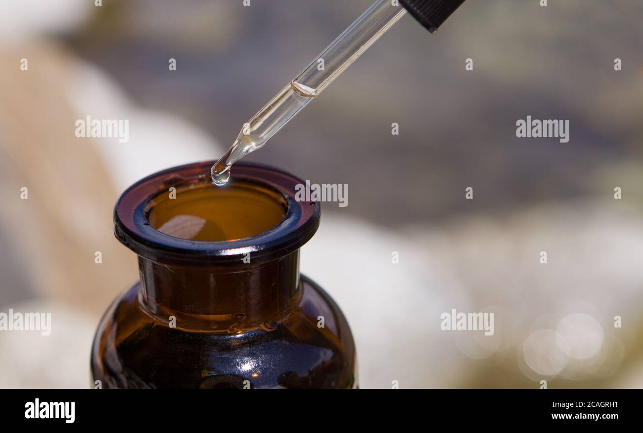 Essential oil falling from glass dropper Stock Photo - Alamy
