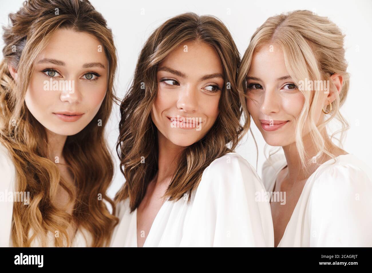 Photo of caucasian pleased three women smiling and looking at camera ...