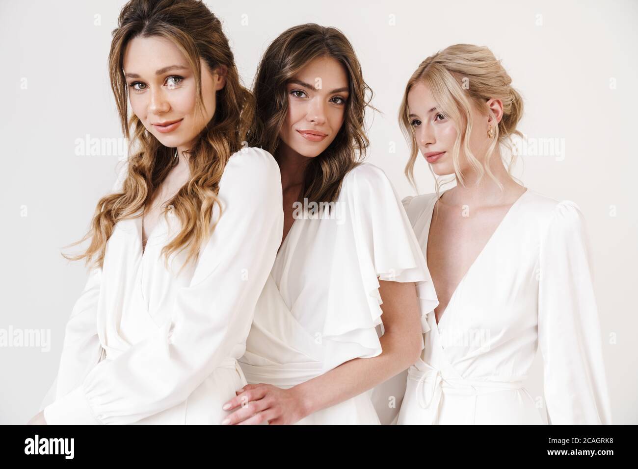 Photo of pleased charming three women hugging and looking at camera ...