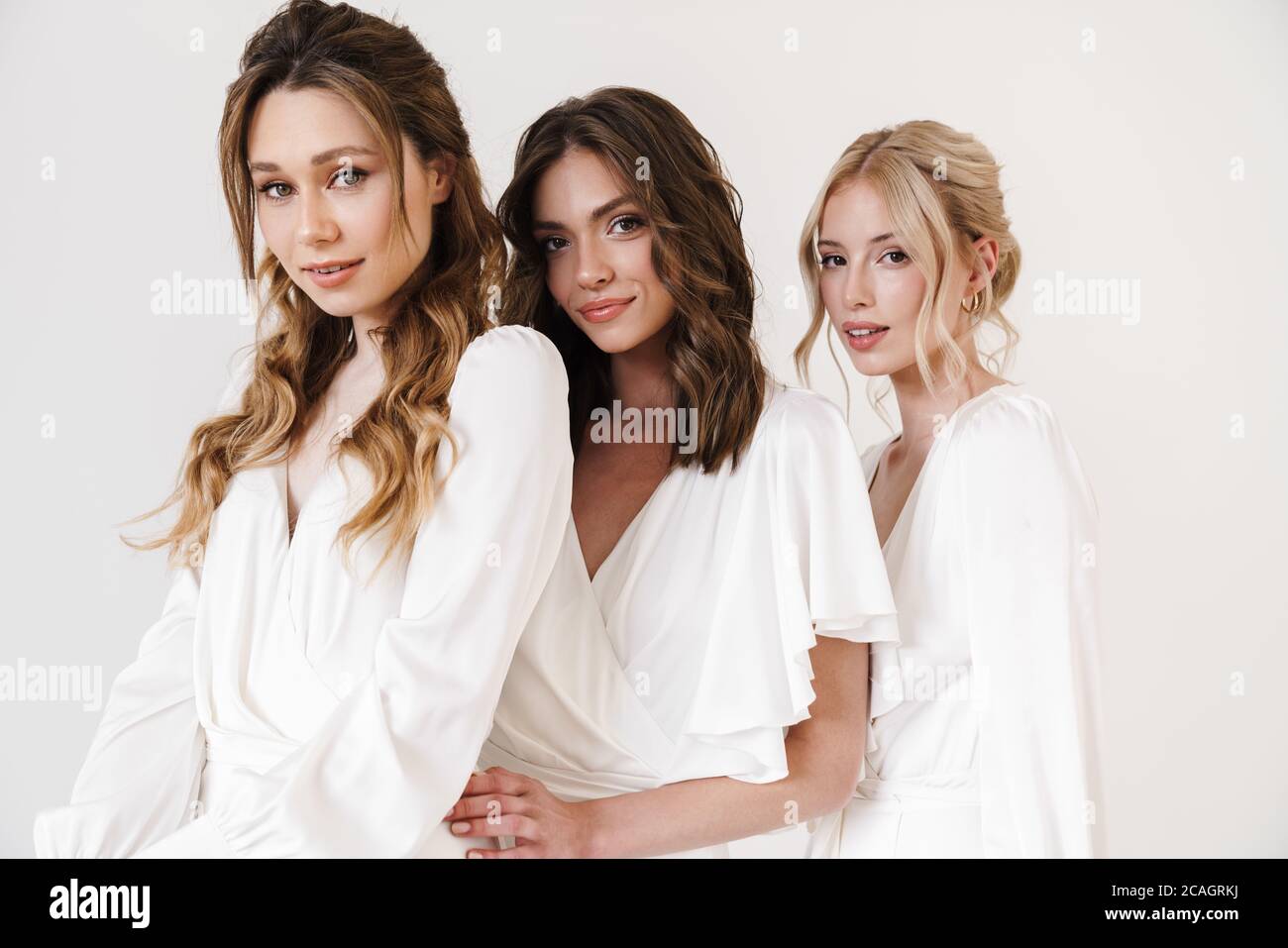 Photo of pleased charming three women hugging and looking at camera ...