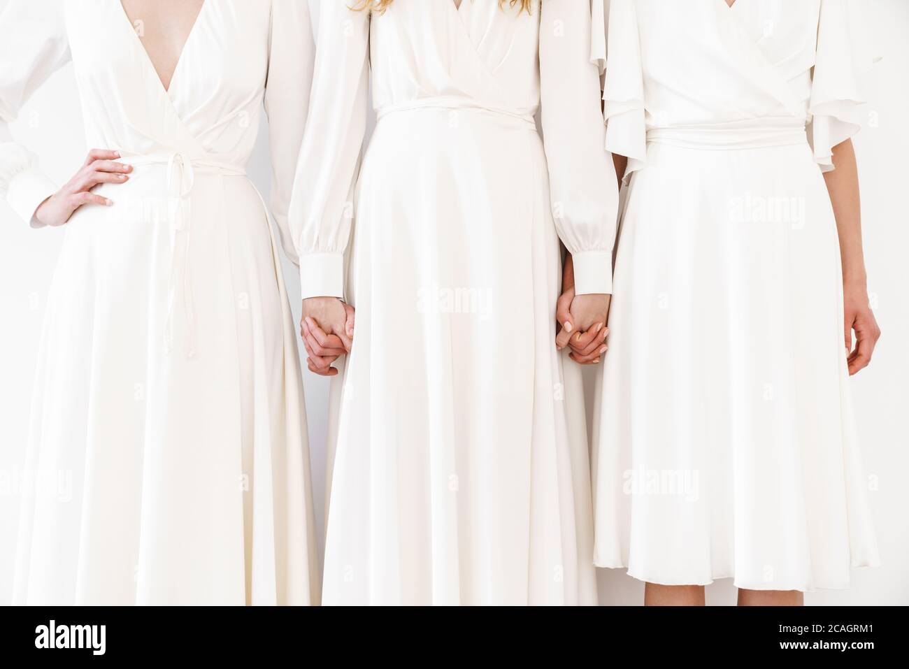 Cropped photo of three women in dresses holding hands together isolated ...