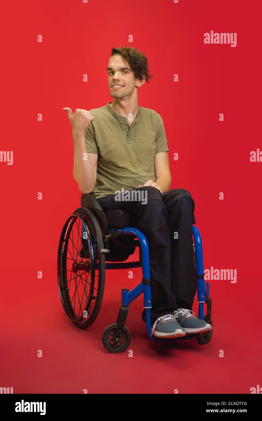 Pointing. Caucasian young disabled man's portrait isolated on red ...