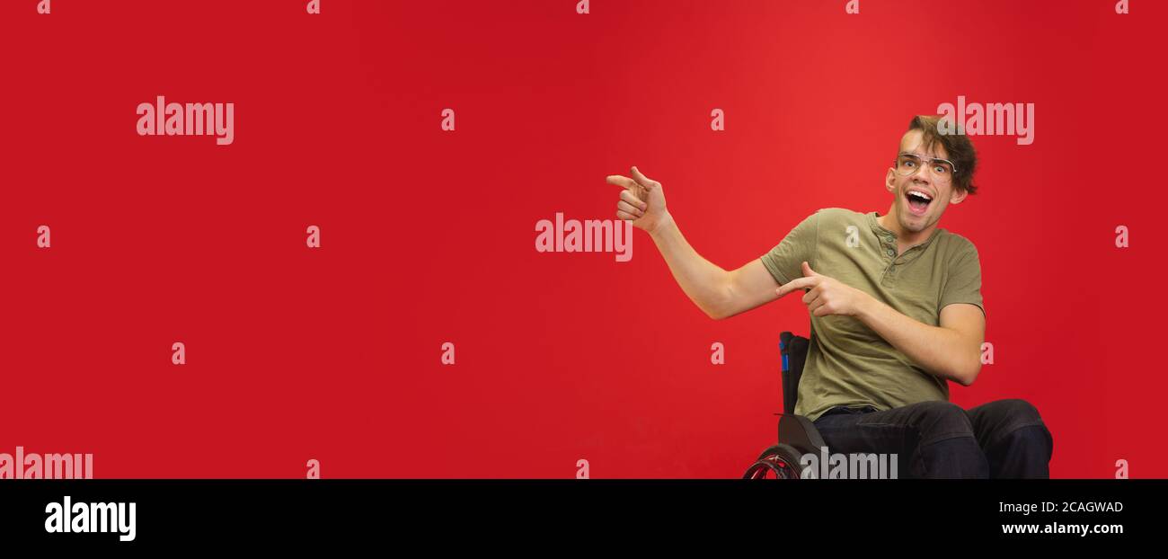 Pointing shocked, flyer. Caucasian young disabled man's portrait on red ...