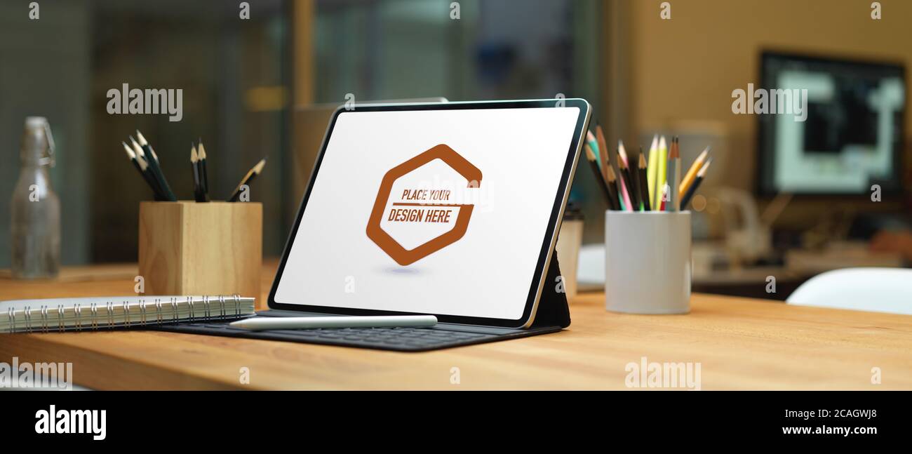 Side view of mock up tablet on wooden table with stationery and copy ...