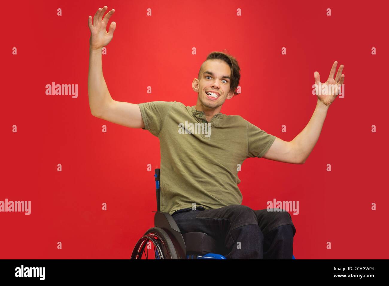 Shows huge. Caucasian young disabled man's portrait isolated on red ...