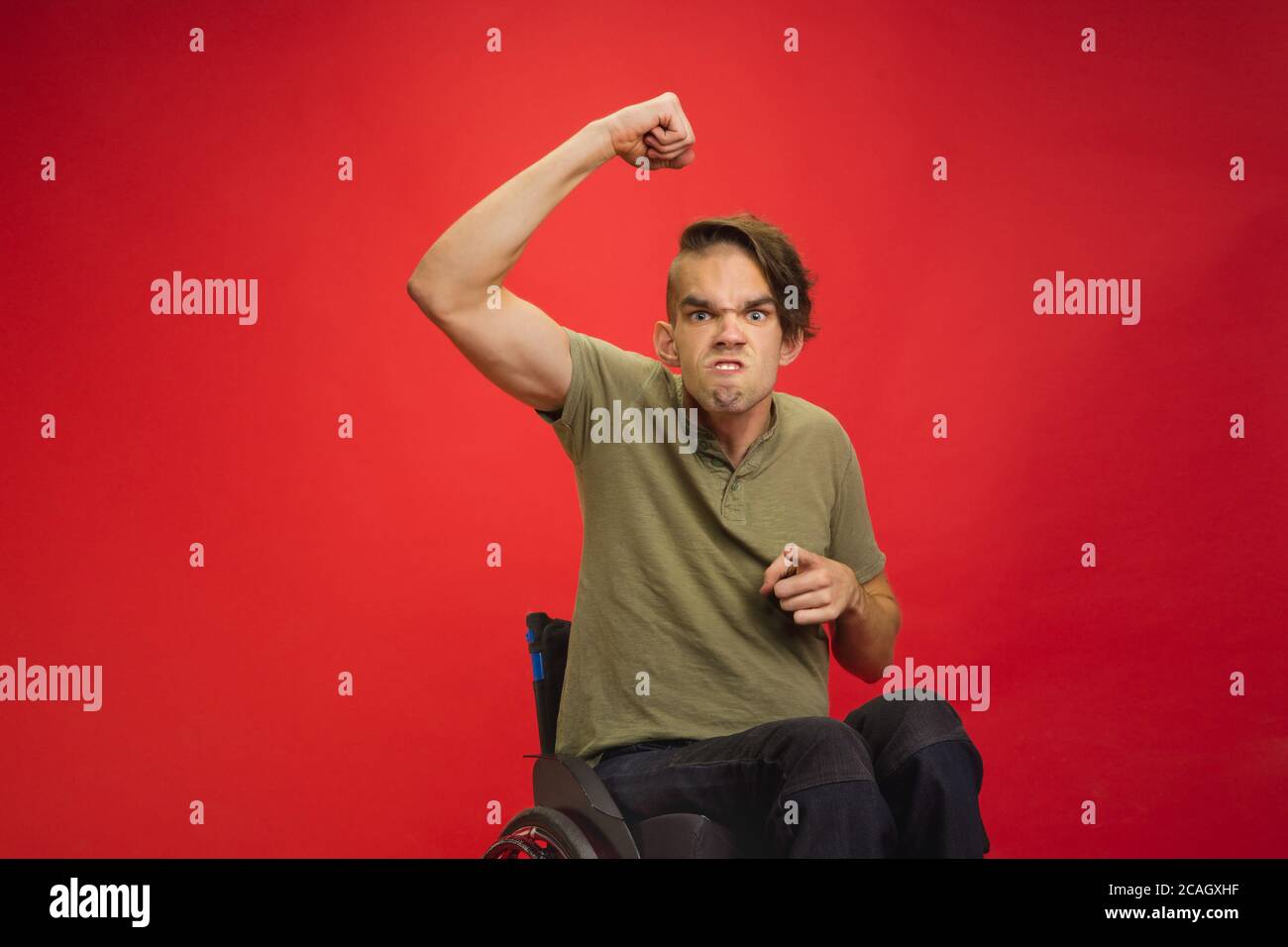 Threatening. Caucasian young disabled man's portrait on red studio ...