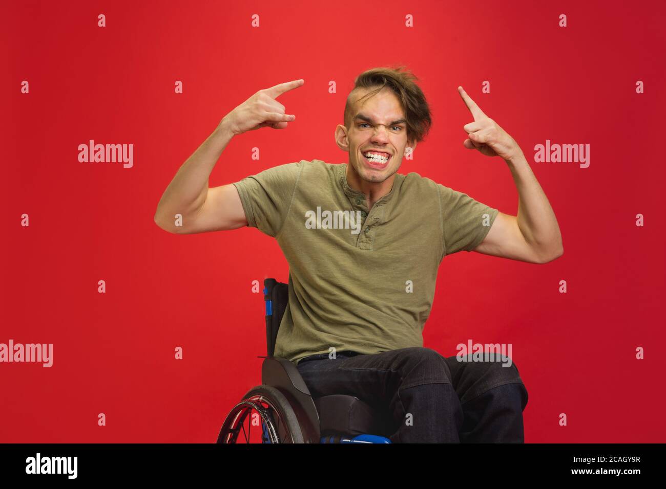 Rock star. Caucasian young disabled man's portrait isolated on red ...