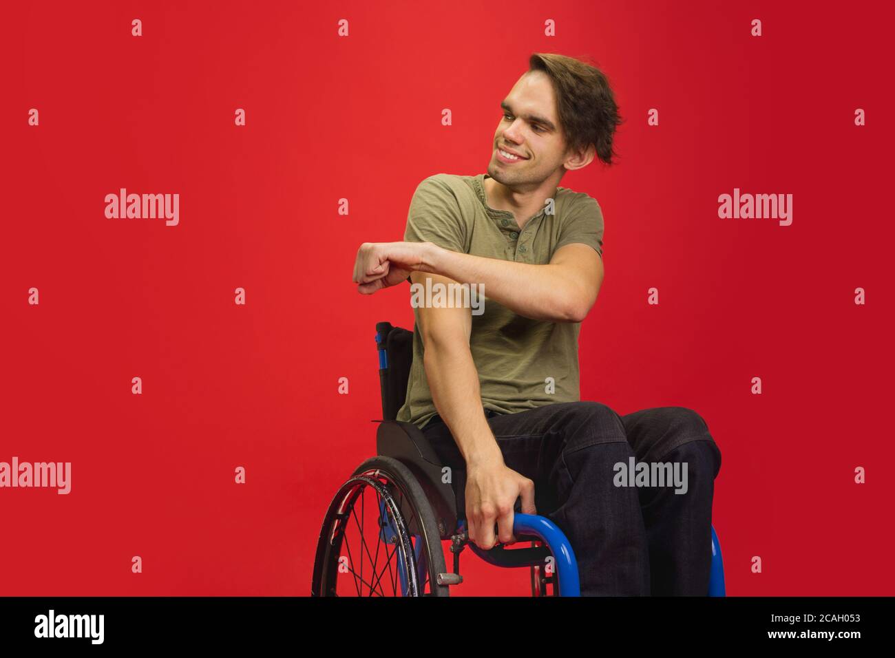 Fist bump, greeting. Caucasian young disabled man's portrait on red ...